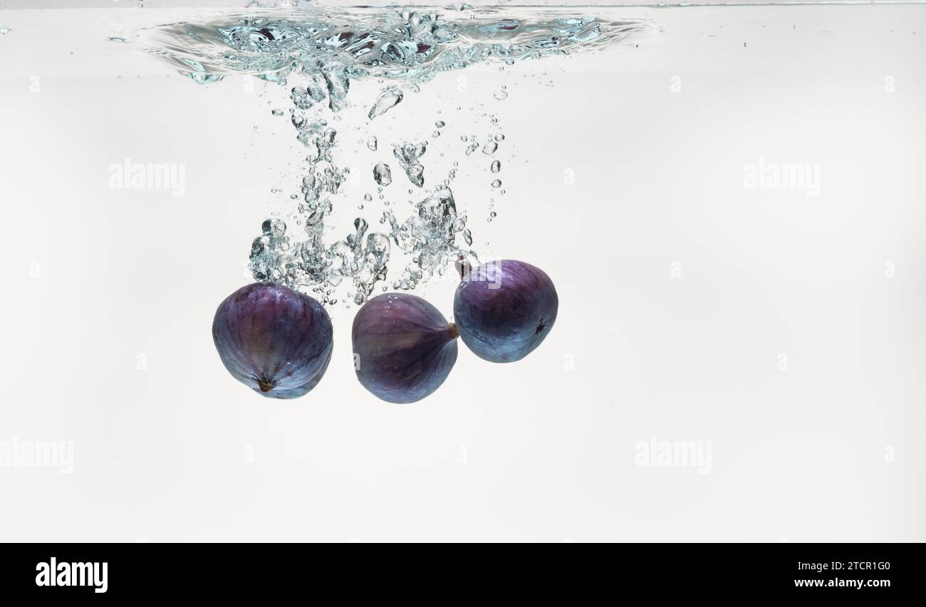 Three figs sinking into water isolated against white background Stock ...