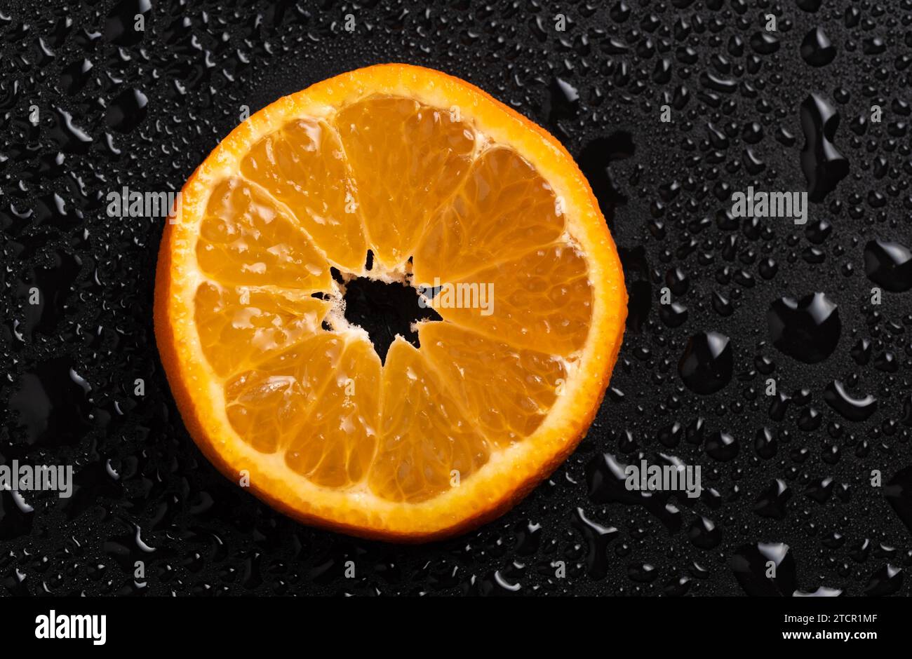 Mandarin slice, detailed closup against black background coverd with ...