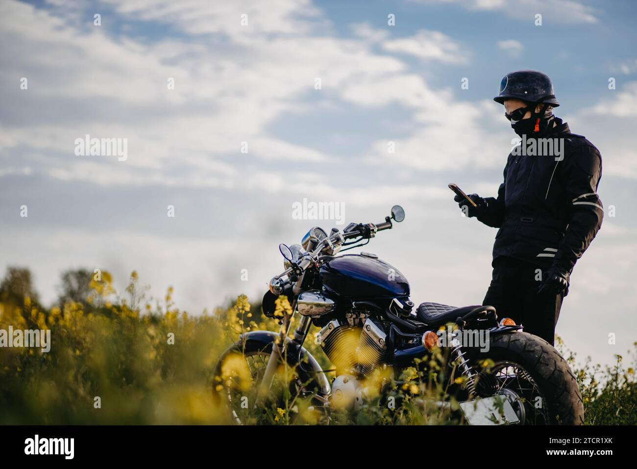 Male motorcyclist in motorcycle outfit with custom bobber motorcycle in ...