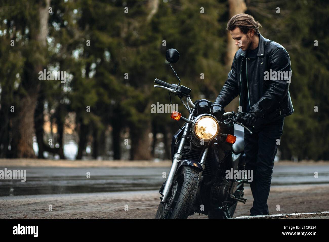 Stylish male motorcyclist in a leather jacket with a classic motorcycle ...