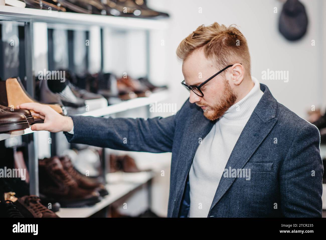 Fashionable man stylist in glasses and a jacket chooses shoes in the ...