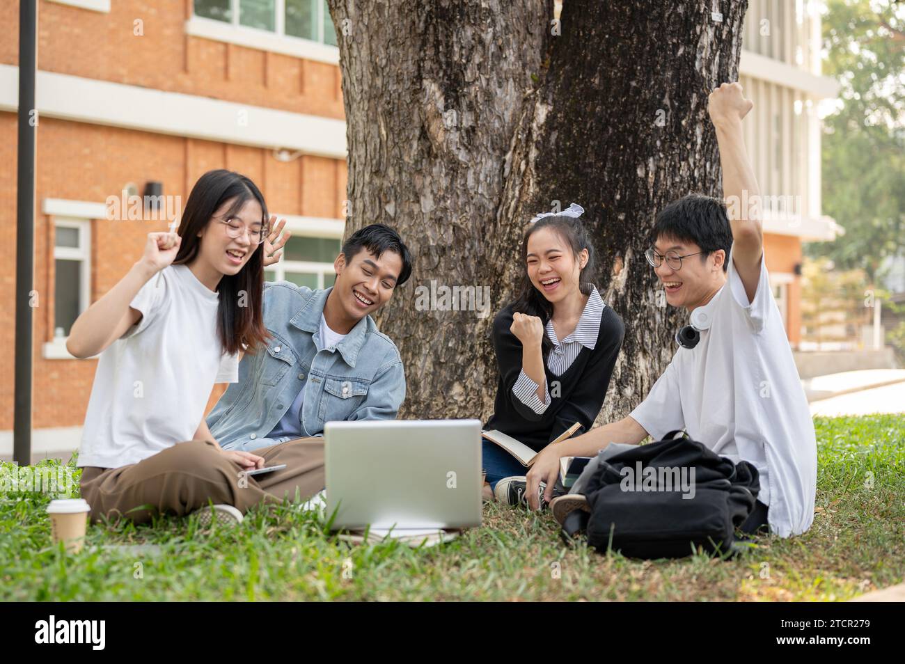 A group of cheerful young Asian students are celebrating their good ...
