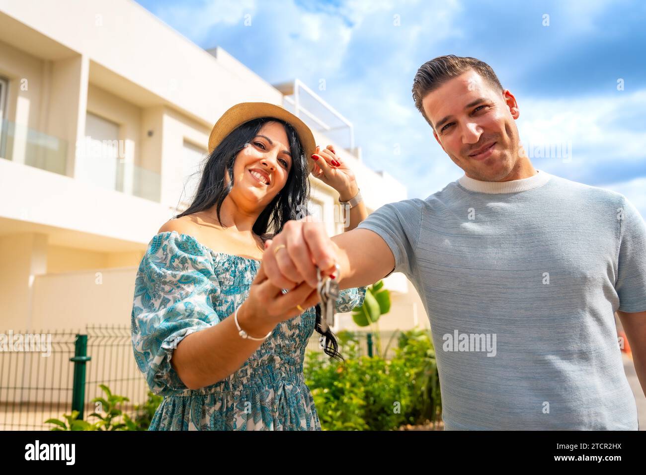 Happy couple showing the keys of a new house standing outside the new ...
