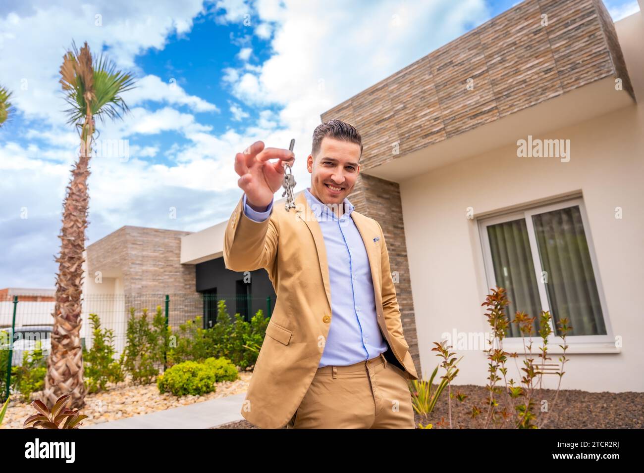 Portrait of a smiling real state agent showing keys of a new house ...