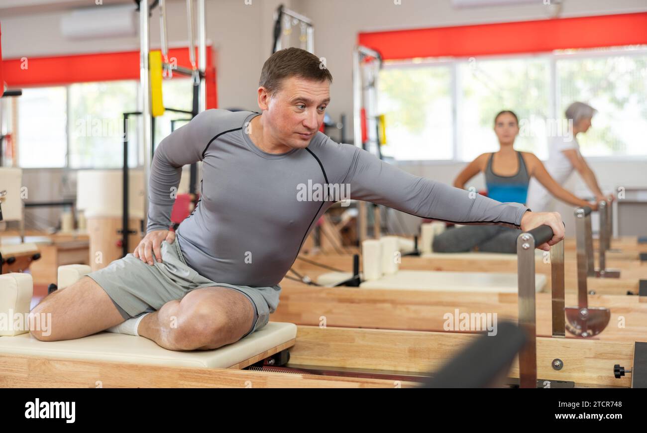 Man performs exercise on reformer to improve coordination, balance, and ...