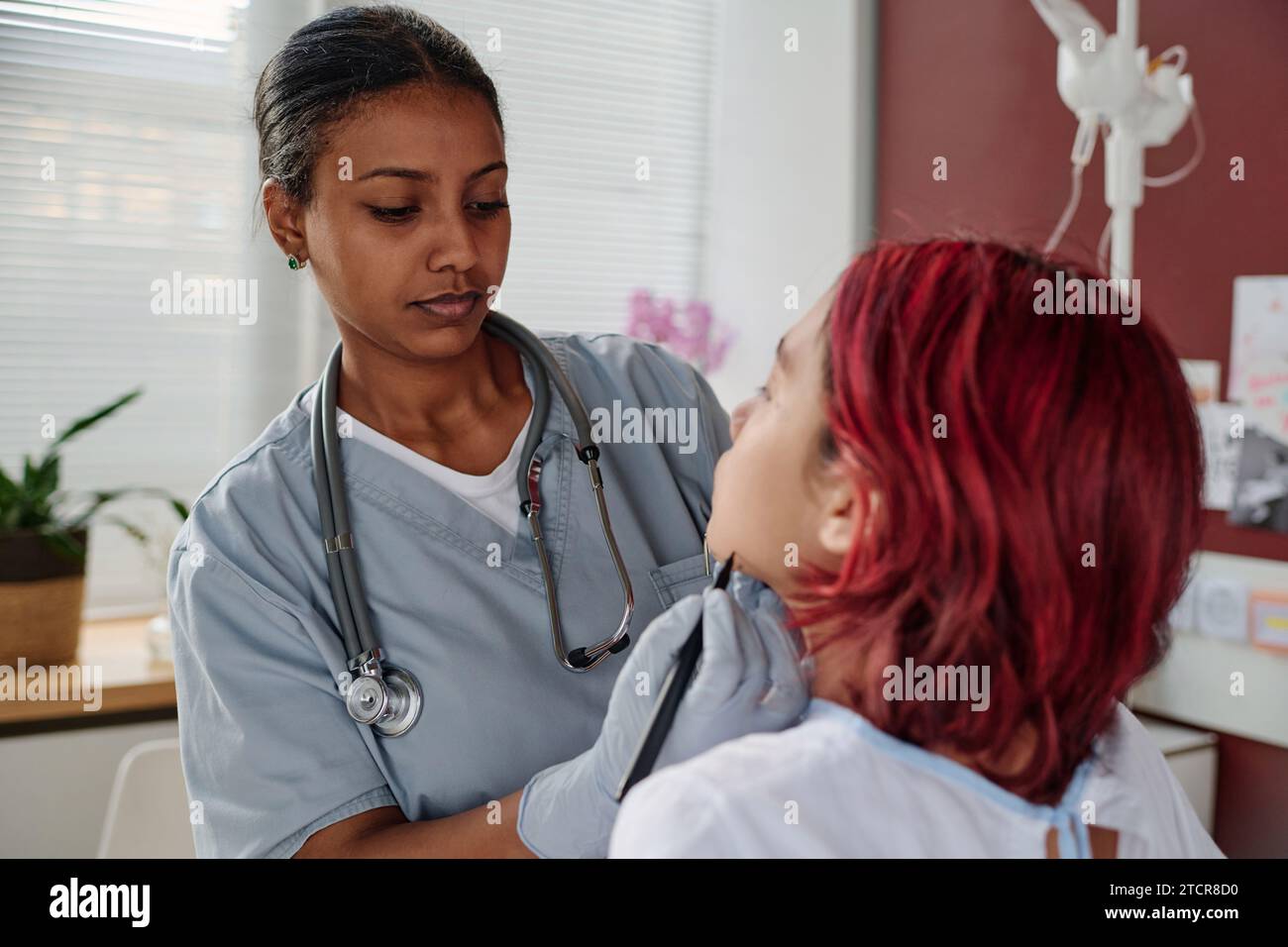 Young African American female plastic surgeon preparing teenage patient ...