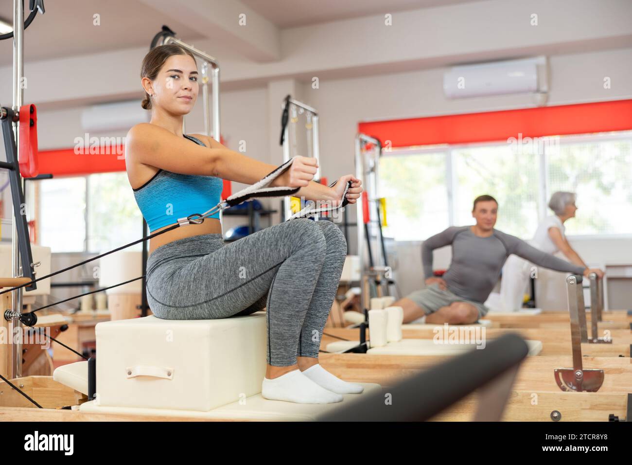 Sports club girl client on reformer with cable and rope performs ...
