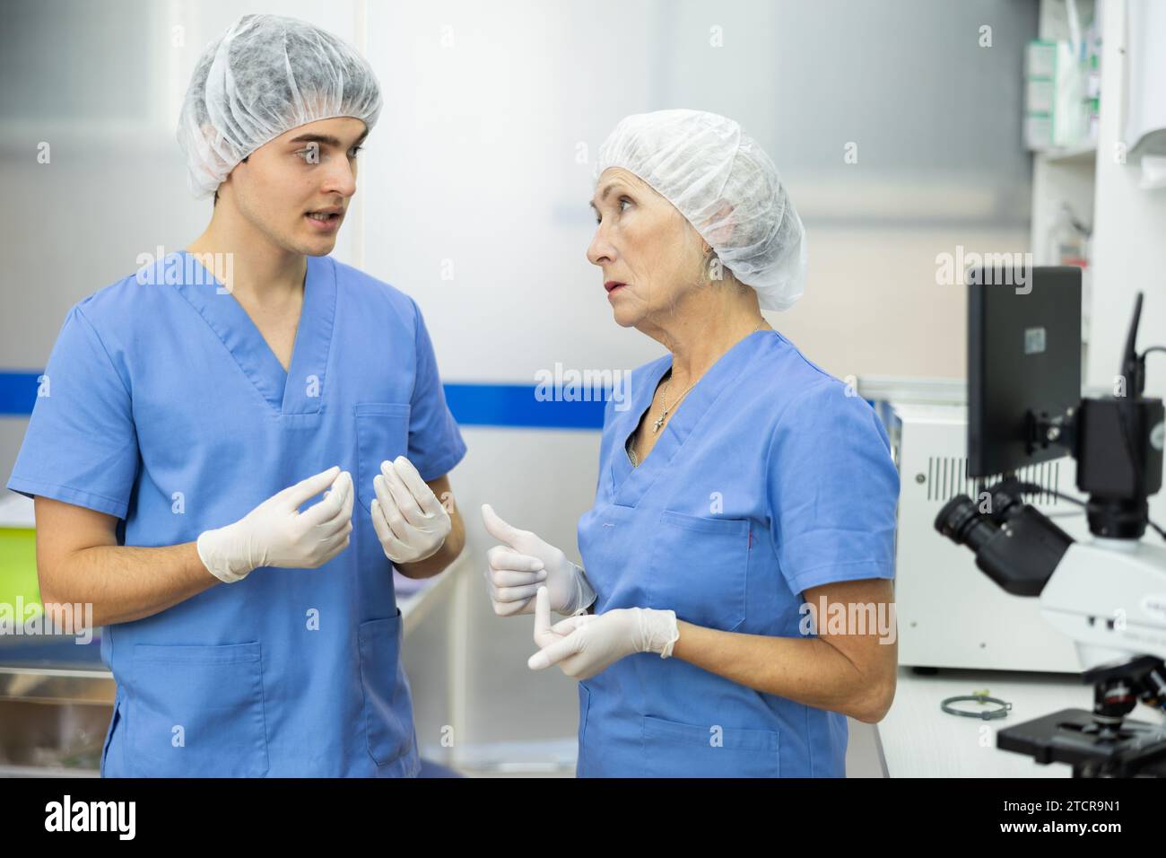 Two professional doctors in blue scrubs talking in medical laboratory ...