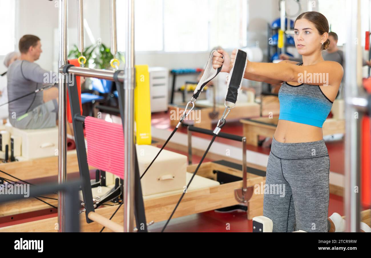 Young woman training her arms using straps Stock Photo - Alamy
