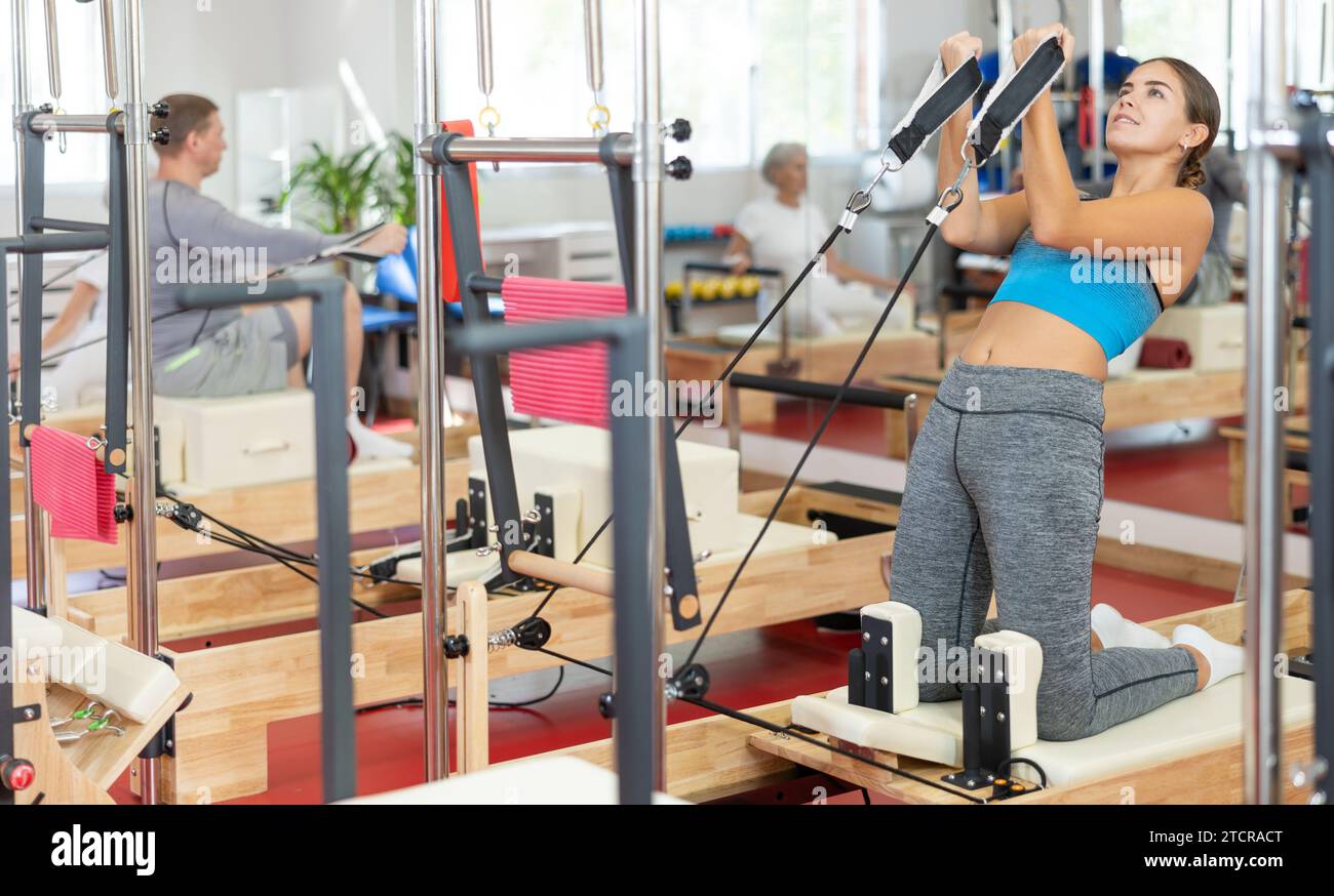 Sports club girl client on reformer with cable and rope performs ...
