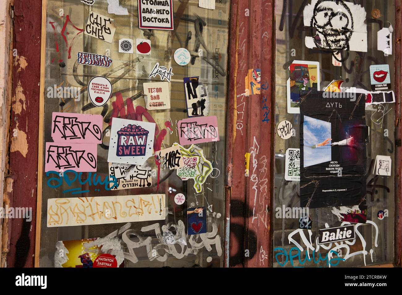 Various colourful stickers and graffiti on a window in abandoned ...