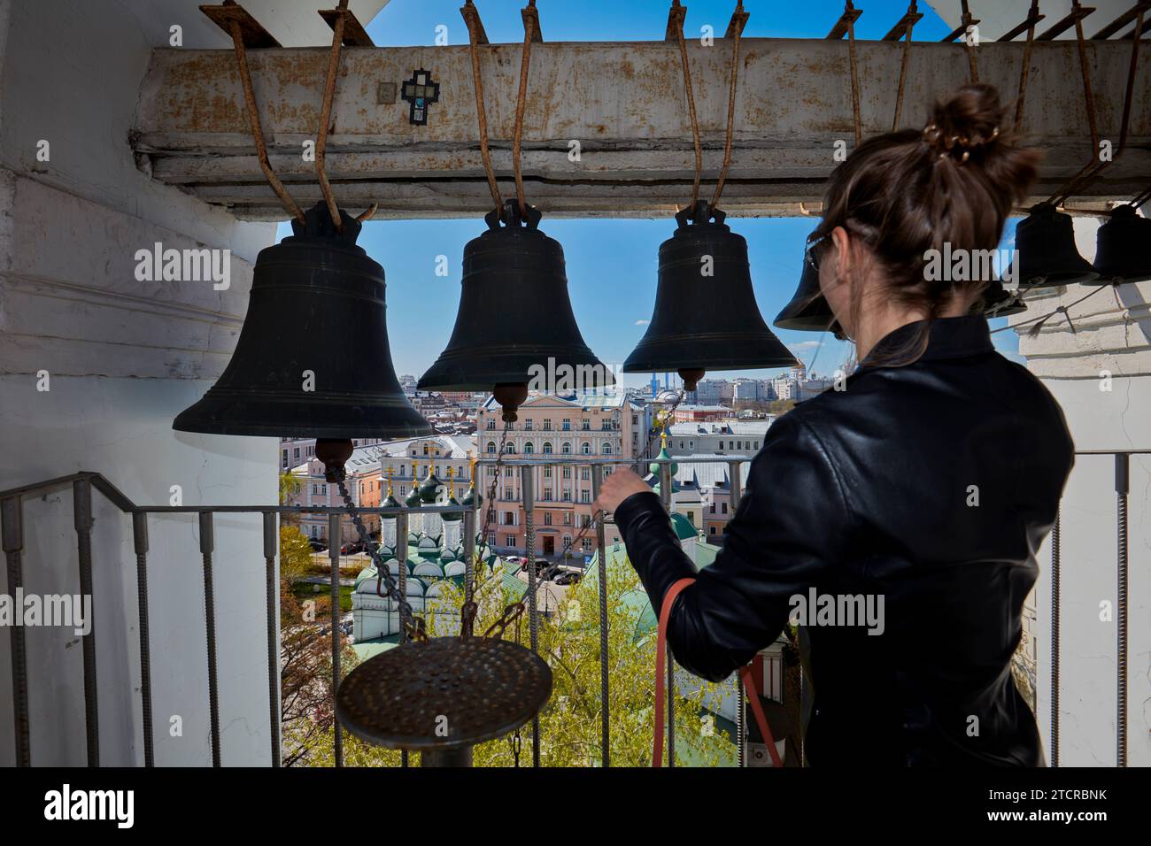 Young woman rings the bells on belfry of the Church of The Beheading of ...