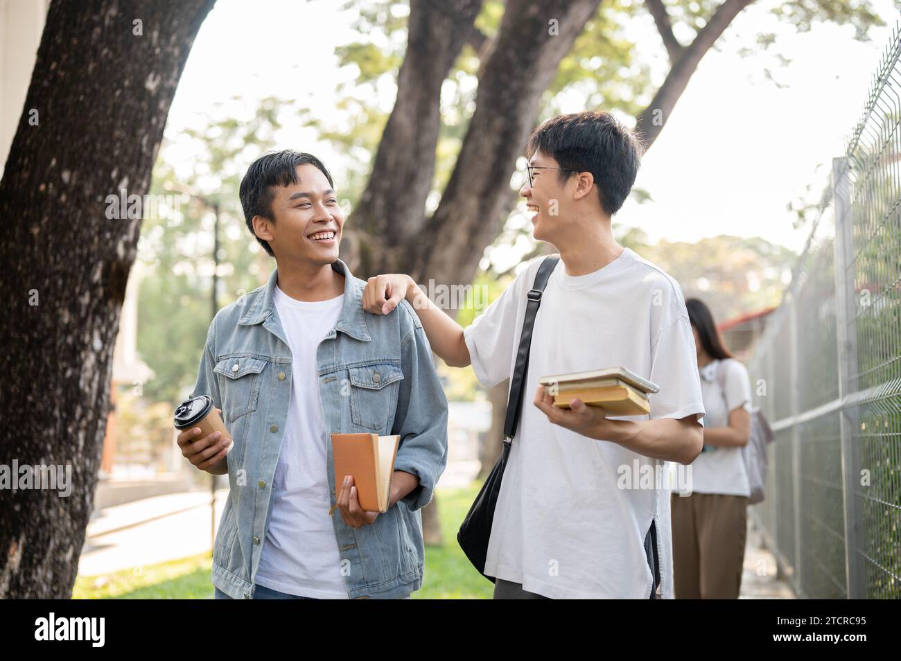 Two young Asian male students best friends are laughing and enjoying ...