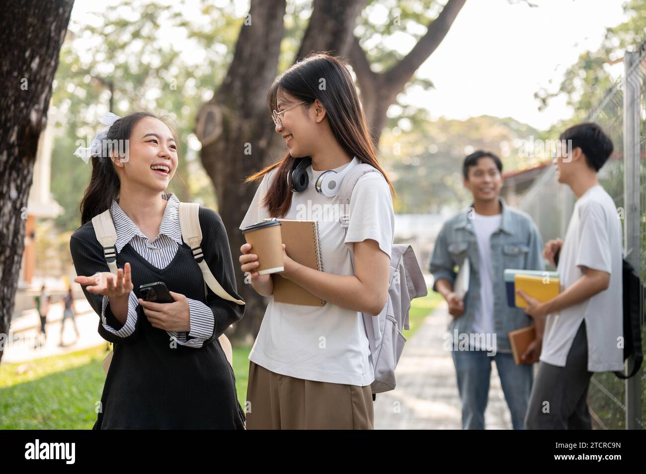 Two young Asian female students best friends are enjoying talking while ...