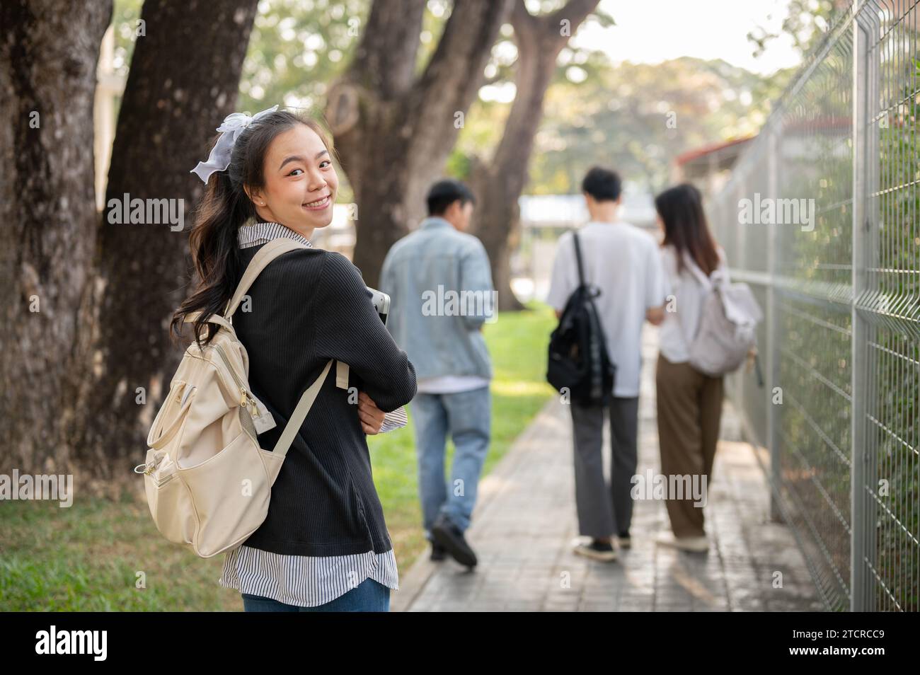 A pretty and smiling Asian female student with her backpack is walking ...