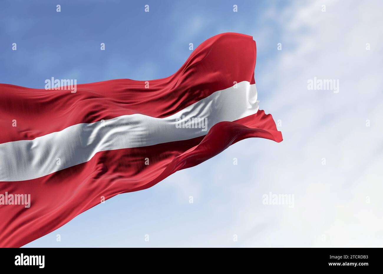 Republic of Latvia national flag waving in the wind on a clear day. Red field with a white ...