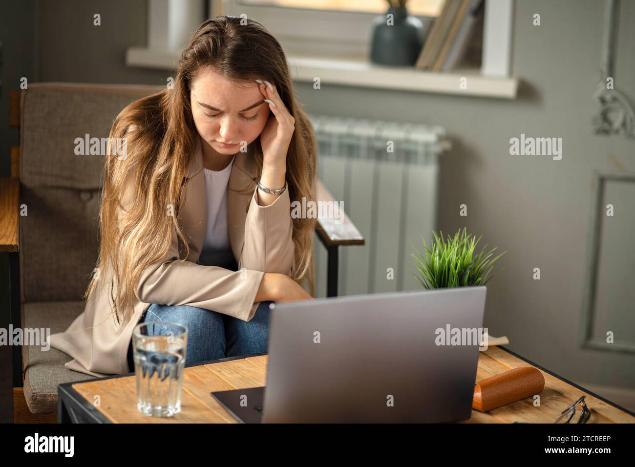 young woman, office worker, uses laptop, feels sudden burst of pain ...