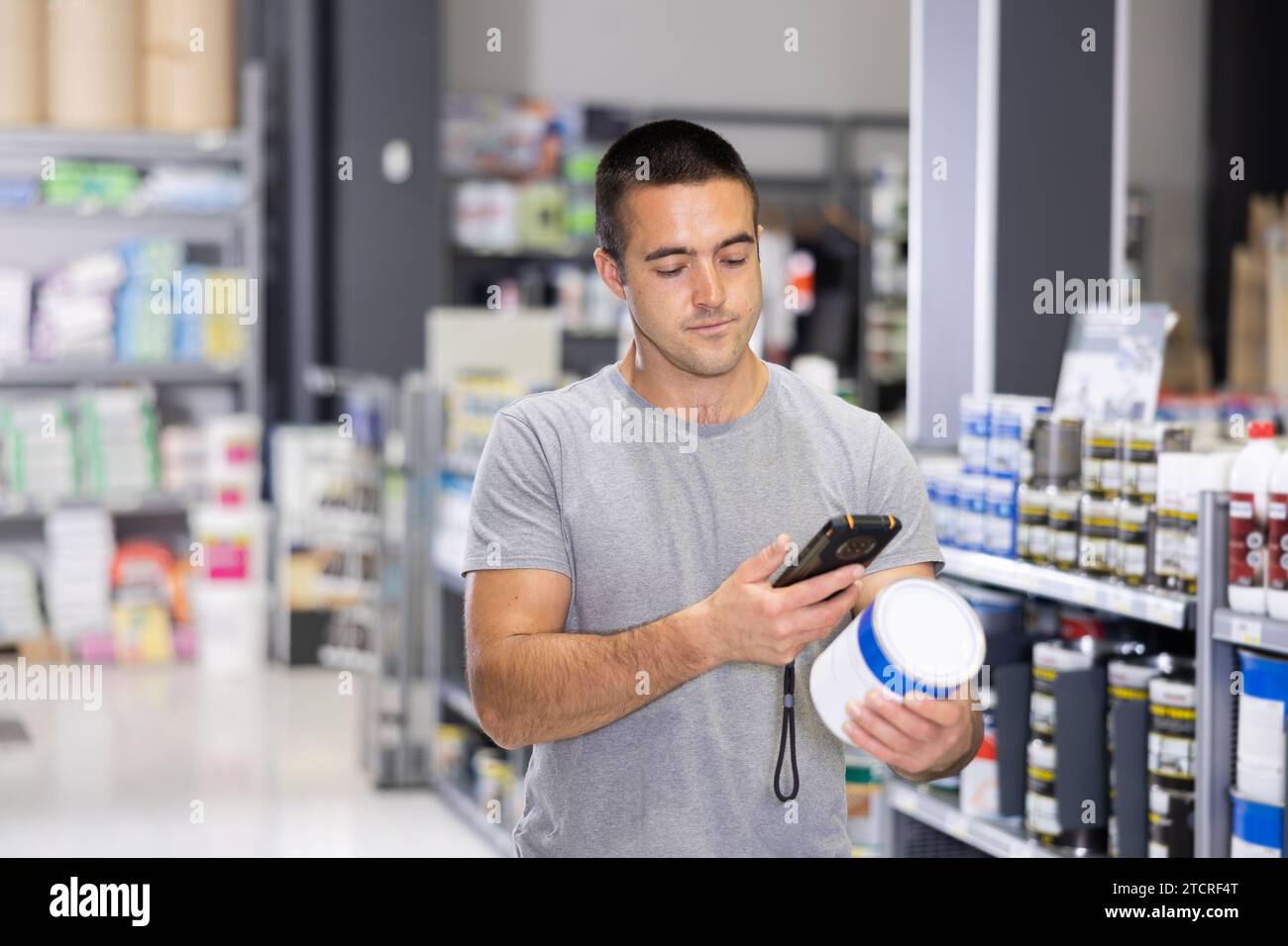 Focused man scanning barcode on paint can in construction hypermarket ...