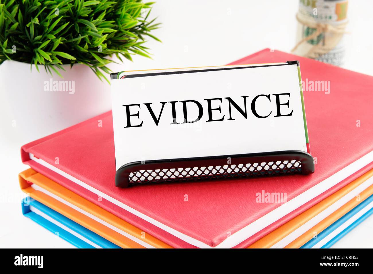 EVIDENCE text on a white business card standing on a stand on notebooks ...