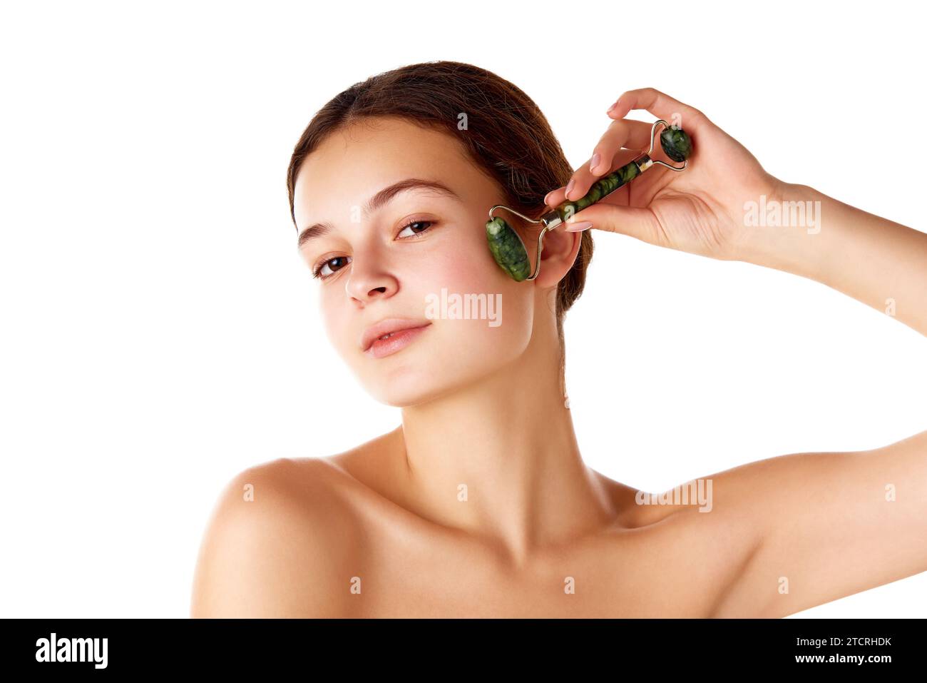 Beautiful young girl taking care after skin, using face massage roller ...