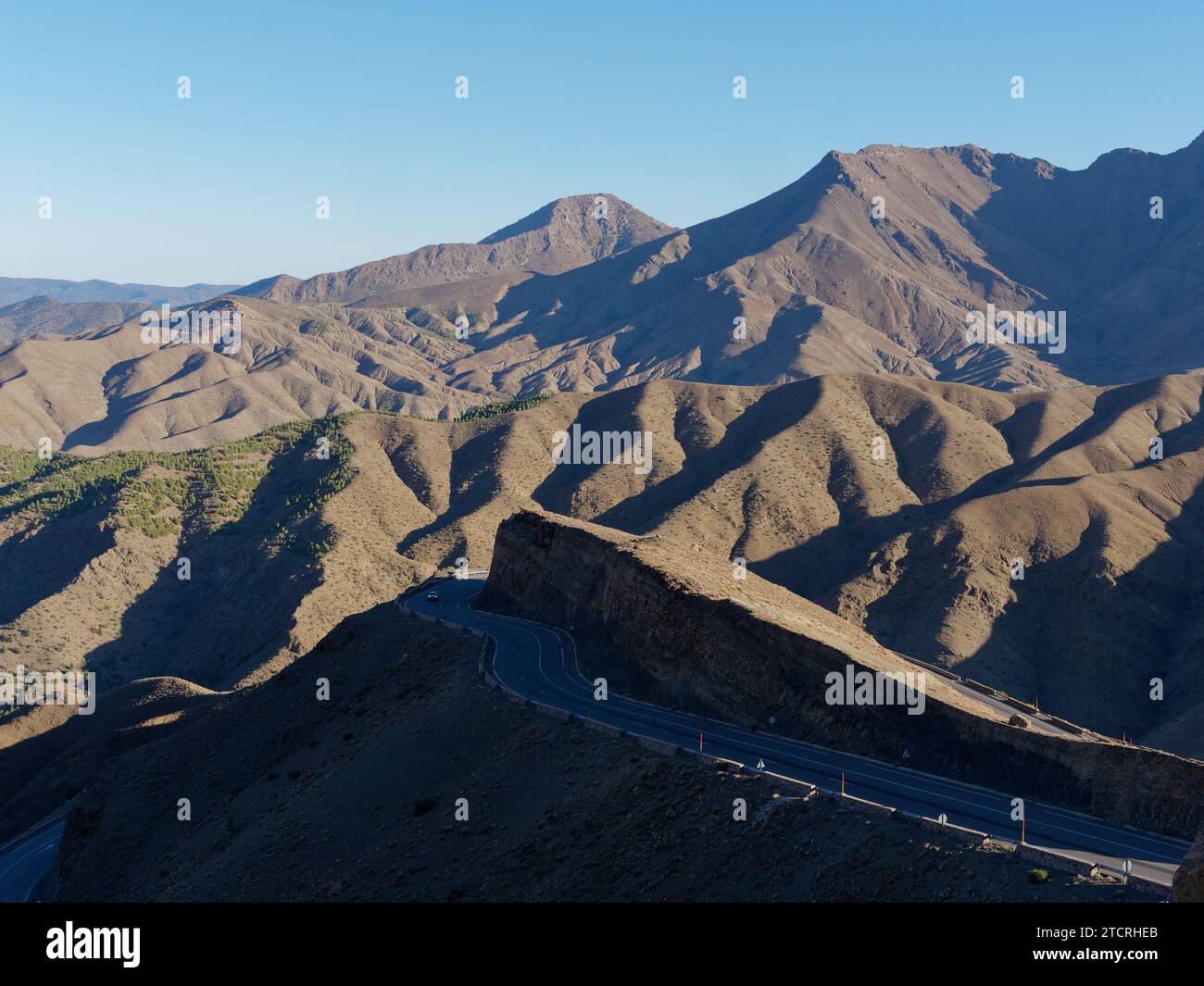 Car with lights on in the morning, on a road covered in shadow in the ...