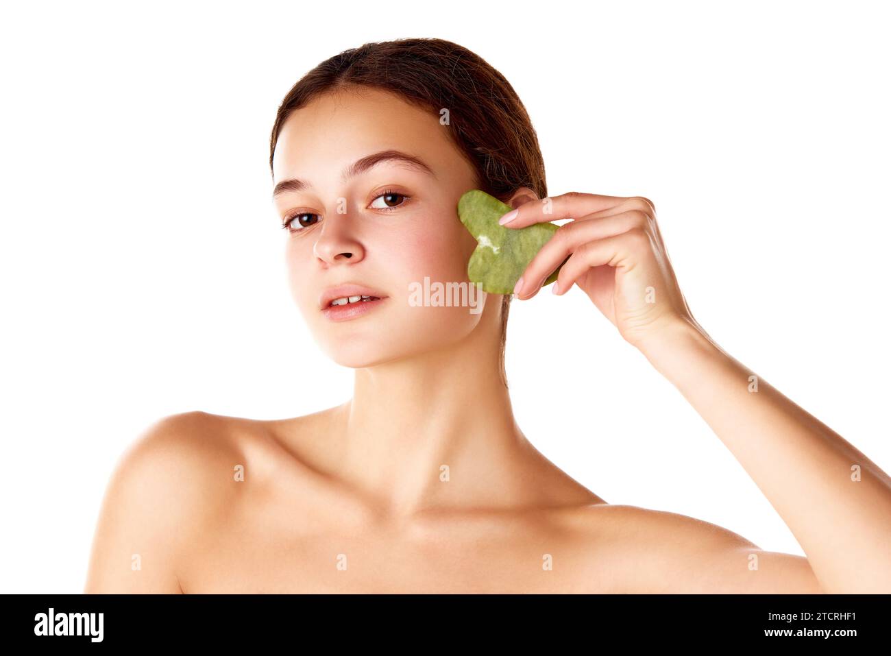 Beautiful young girl taking care after skin, using face massage tool ...