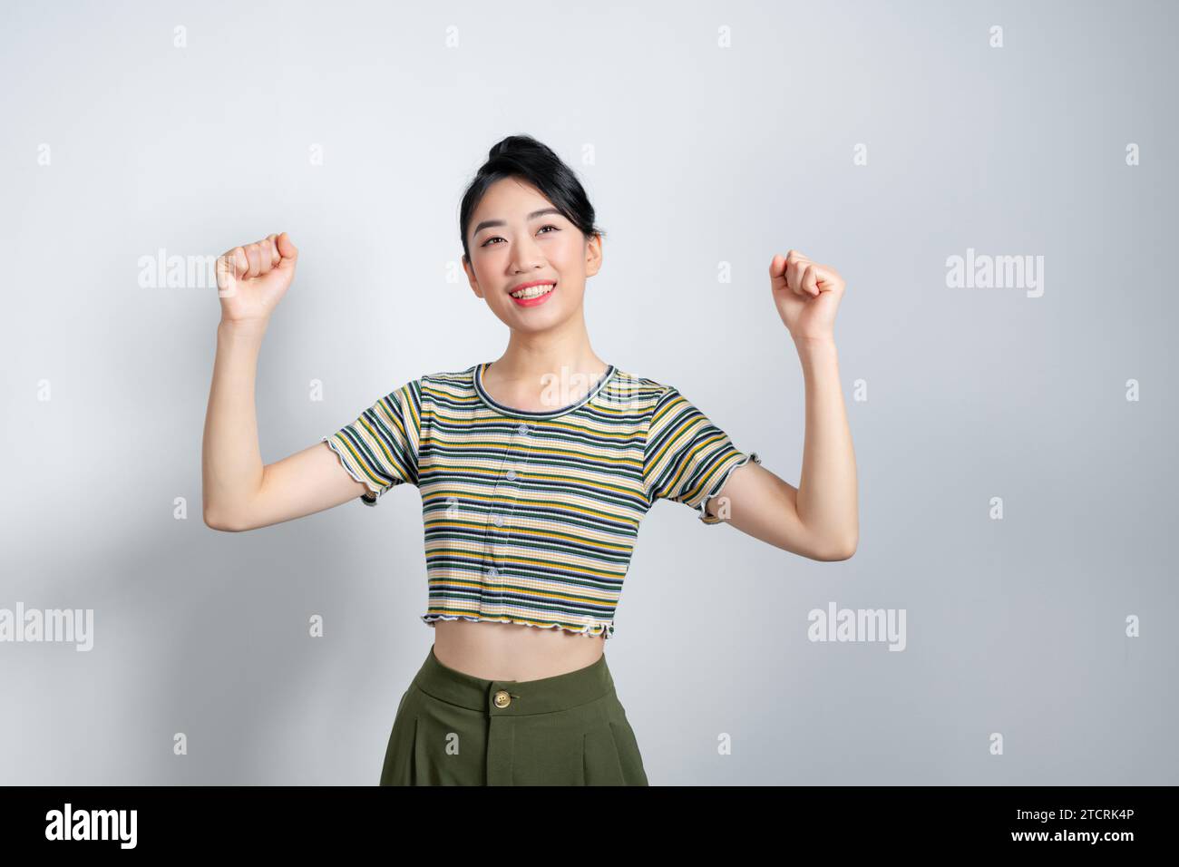 Young asian woman raising arms while smiling and screaming to celebrate ...