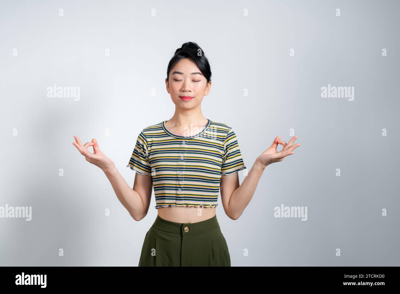 woman meditates indoor, keeps hands in mudra gesture, has eyes closed ...