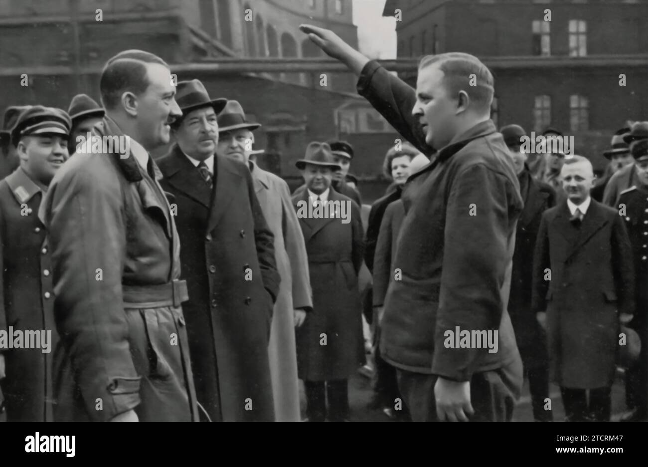During a factory visit, Adolf Hitler is greeted by a representative of ...