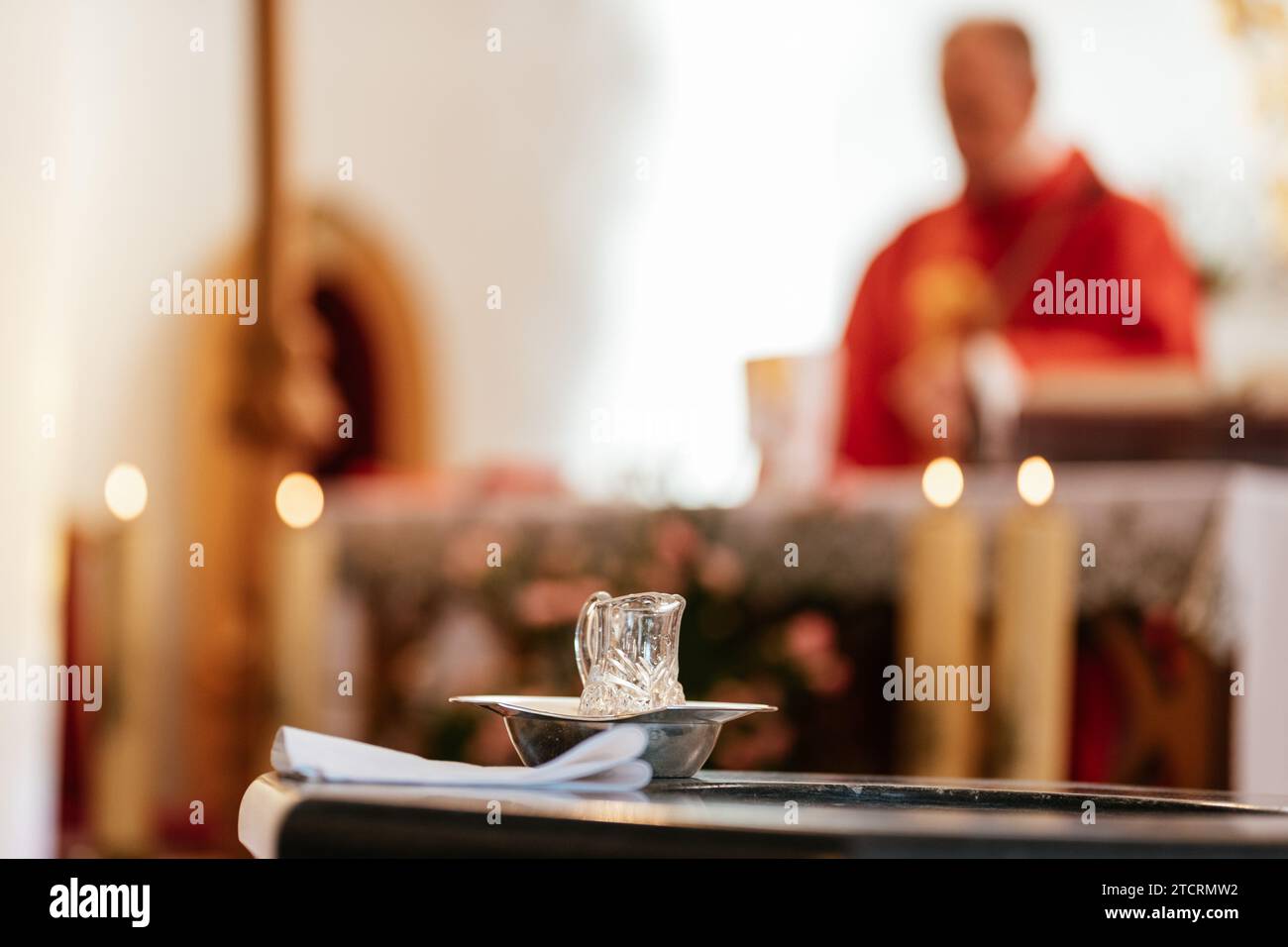 Holy water during baptism catholic mass with priest in the background ...