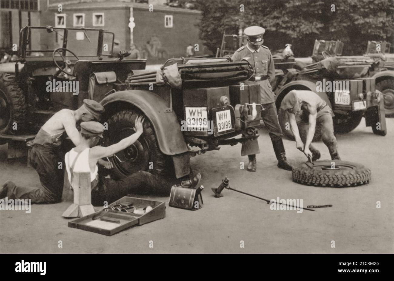 On a city street, a German soldier inspects military vehicles before a ...