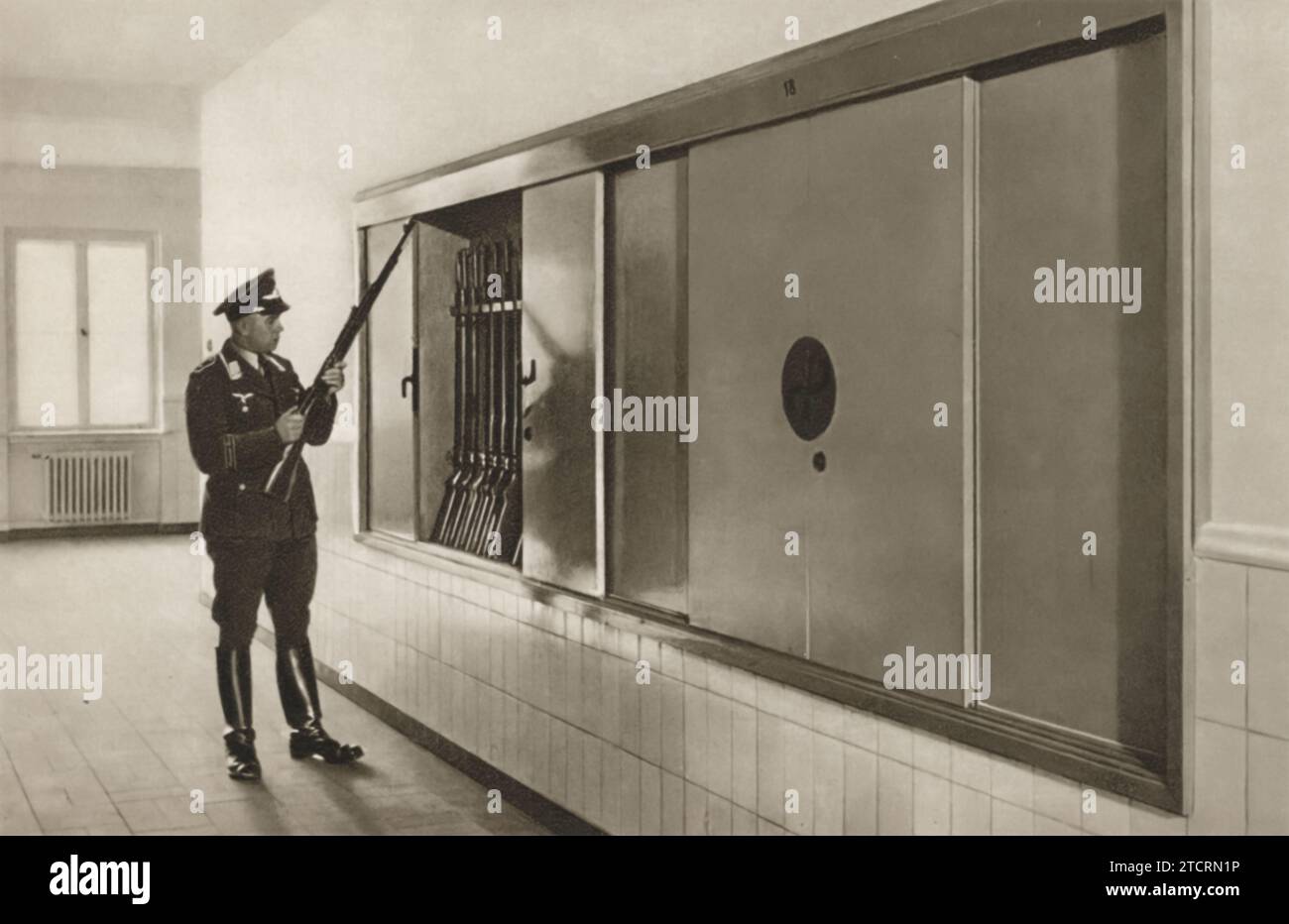 In this image, a German Sergeant meticulously inspects rifles stored in ...