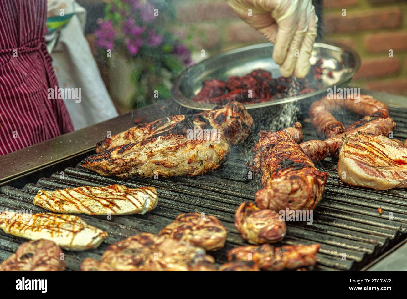 Salting meat during a barbeque. Beef, chicken, belly and sausages ...