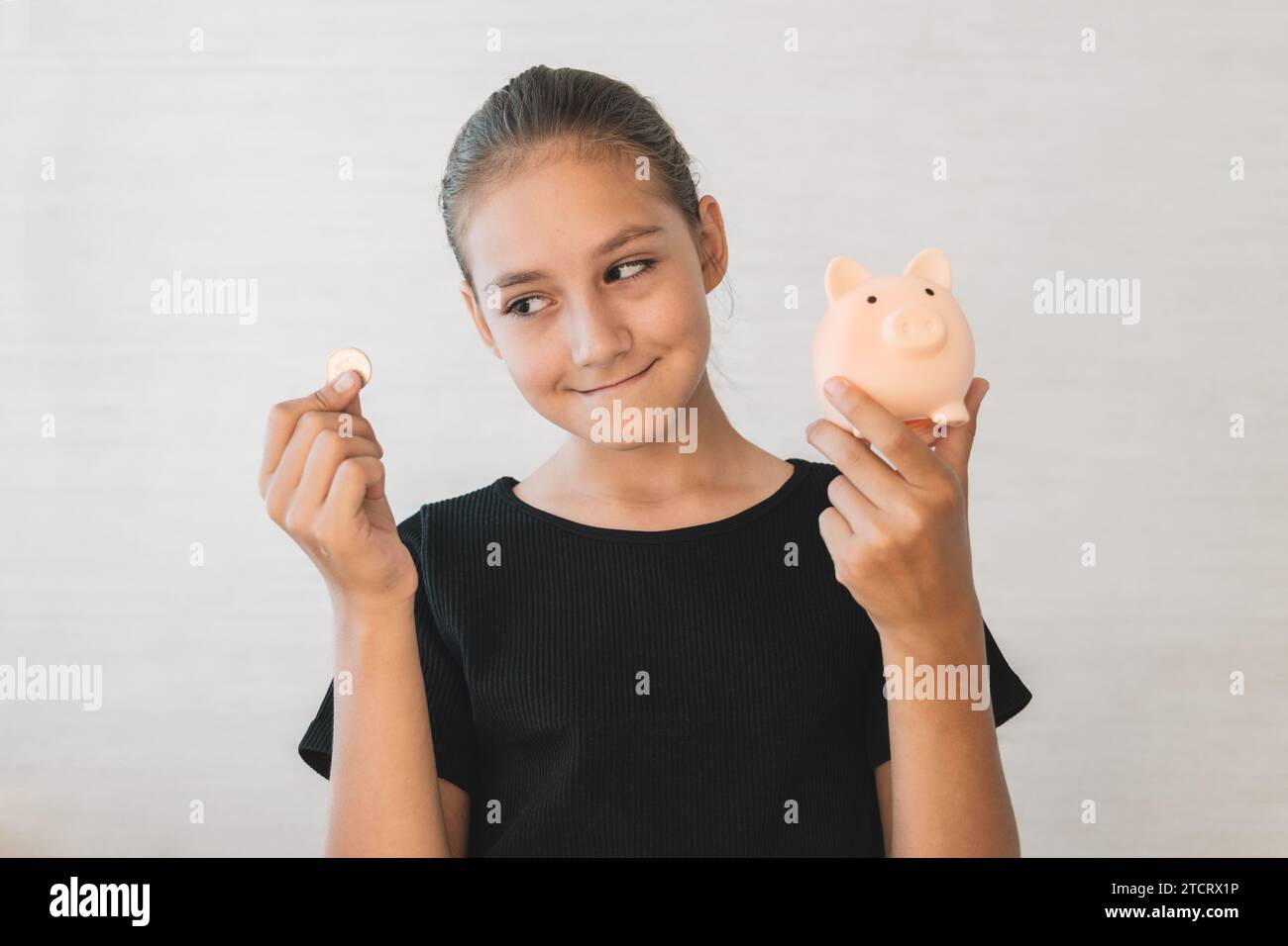 Happy excited teen girl saving money, dropping coin into pink piggy ...