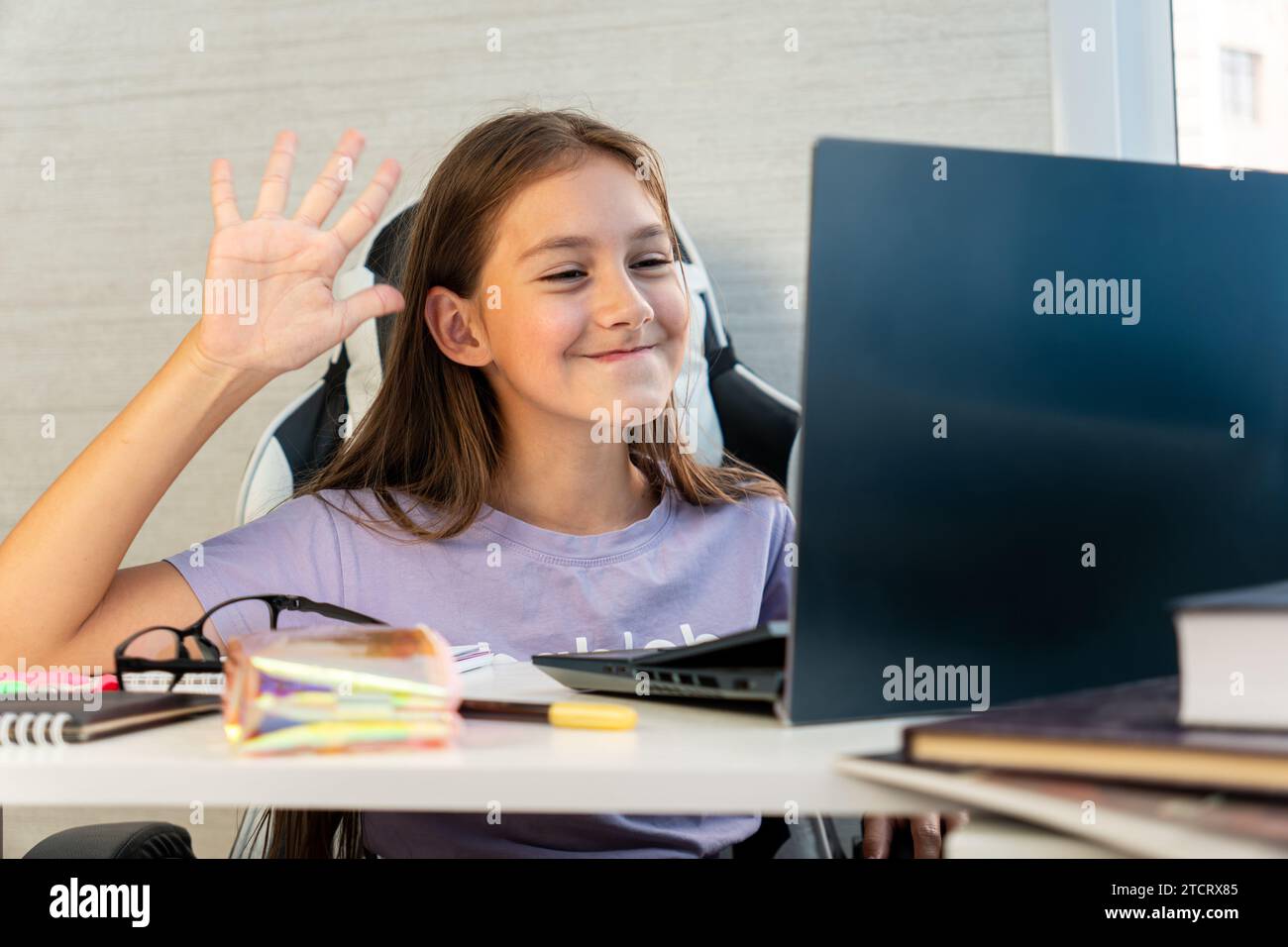 beautiful teenage girl sits in front of laptops. Teenage girl waves her ...
