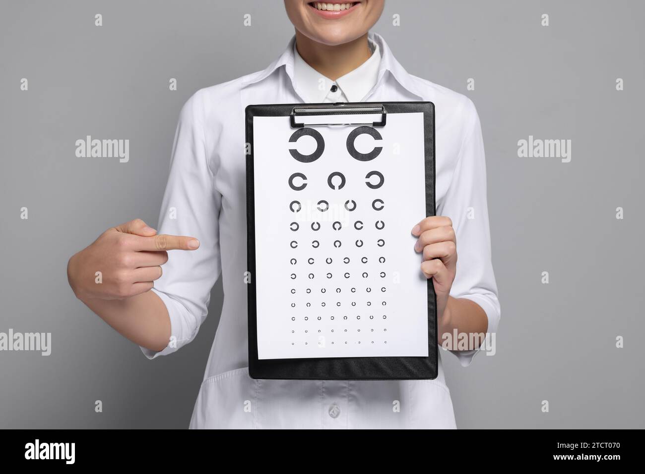 Ophthalmologist pointing at vision test chart on gray background ...