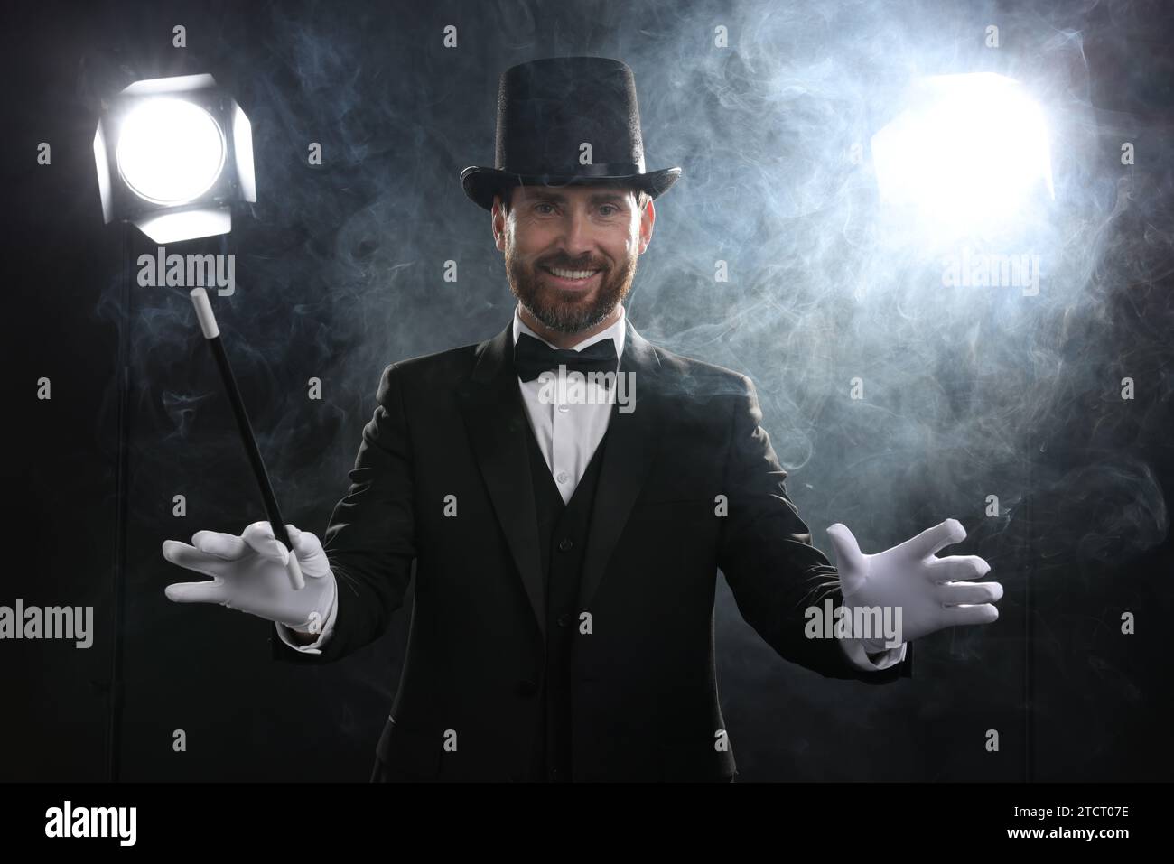 Happy magician with wand in smoke on stage Stock Photo - Alamy
