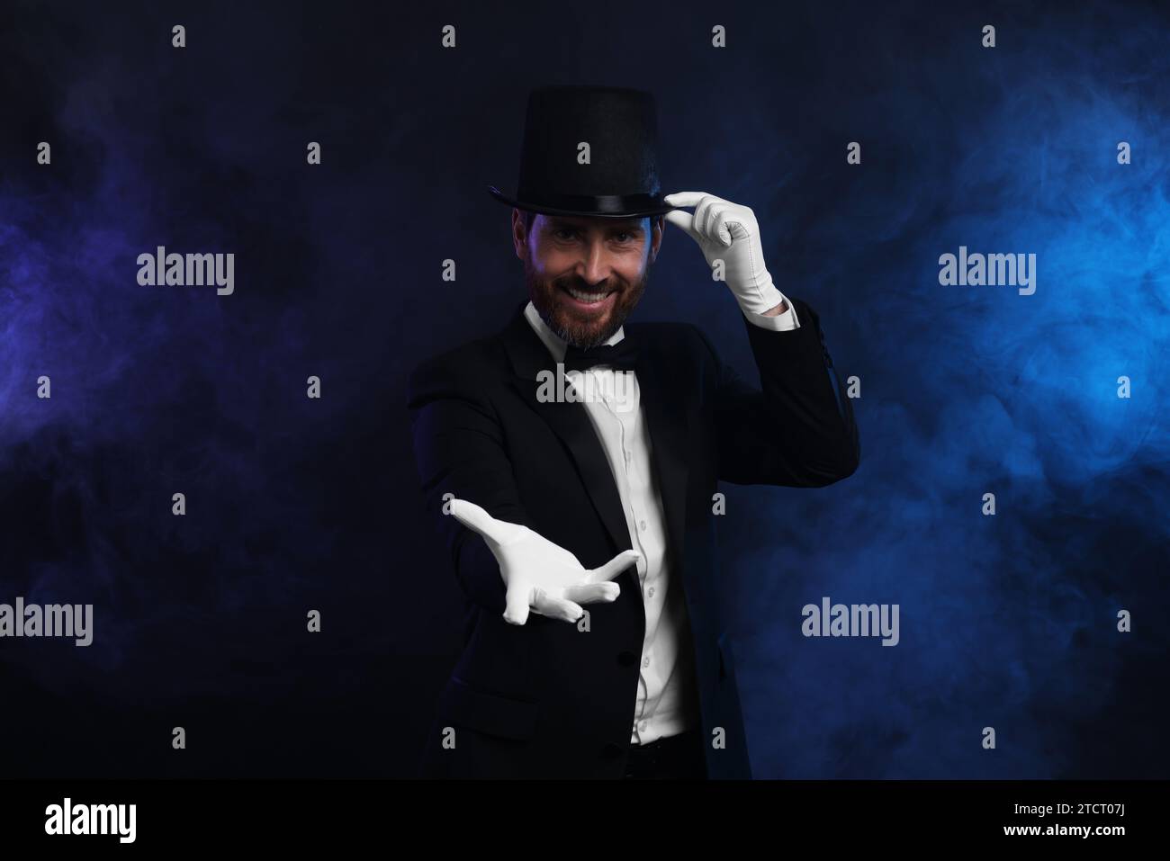 Happy magician wearing top hat in smoke on dark background Stock Photo ...