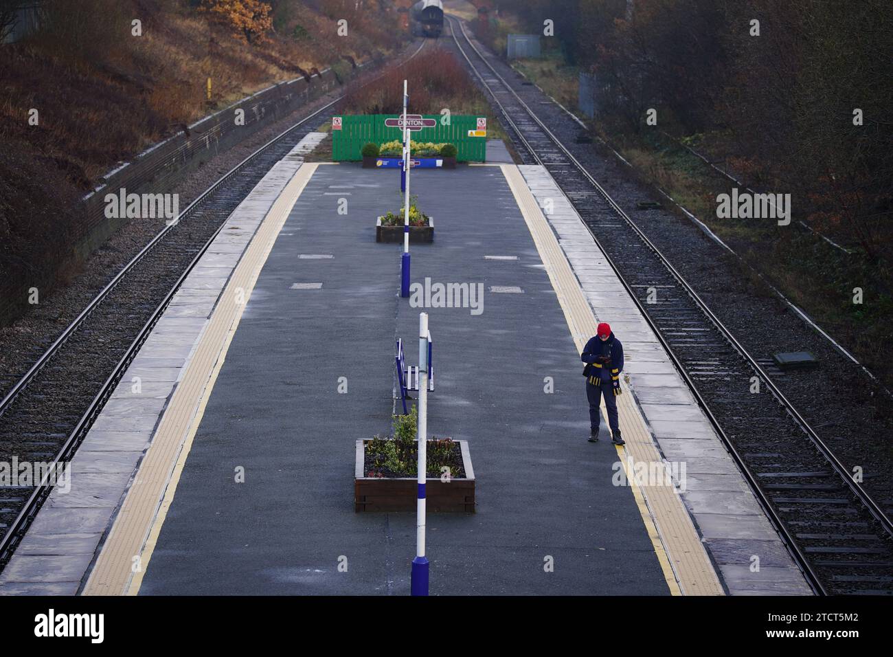 A passenger waits for a train at Denton railway station in Greater ...