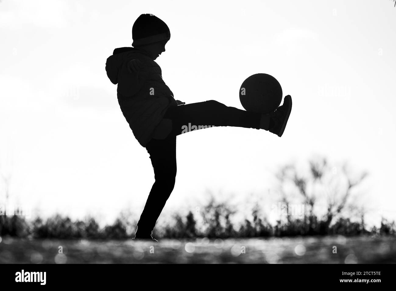 Silhouette of young boy playing football Stock Photo - Alamy