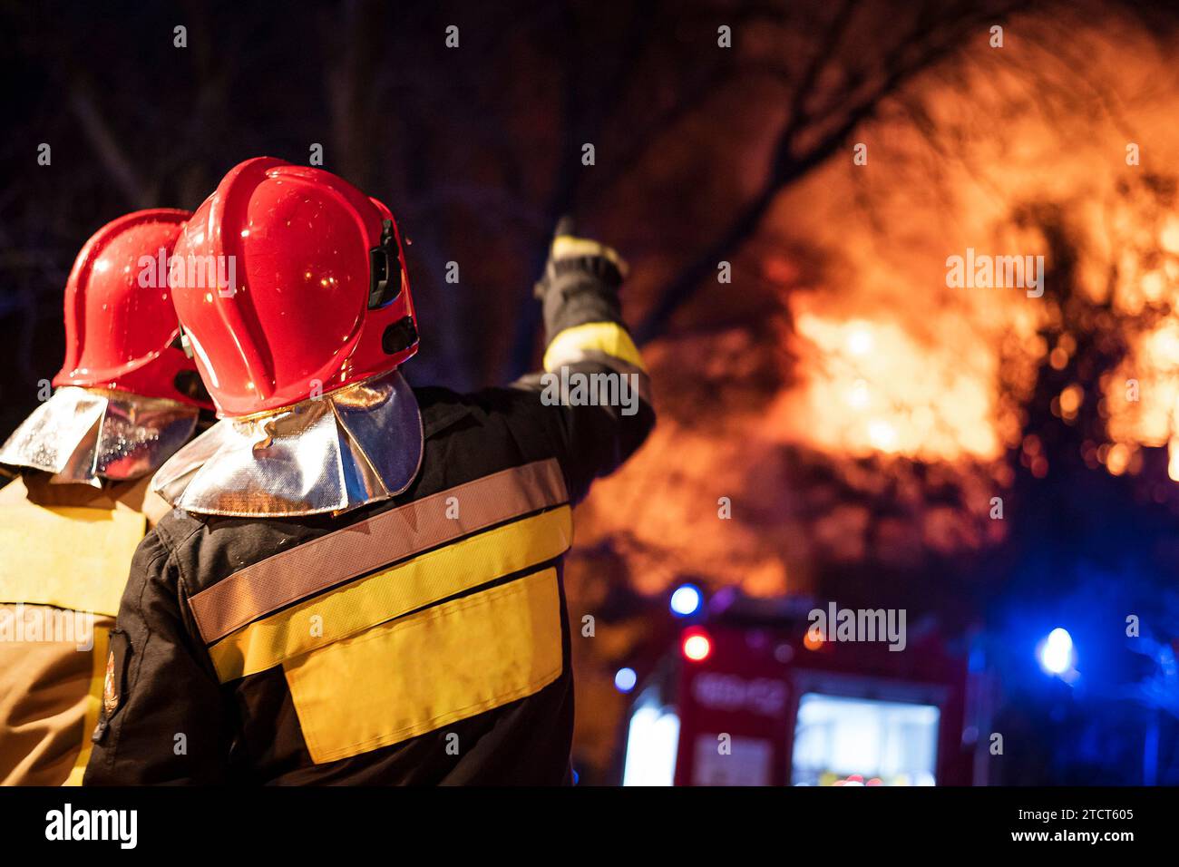 Two firefighters in front of a burning house Stock Photo - Alamy