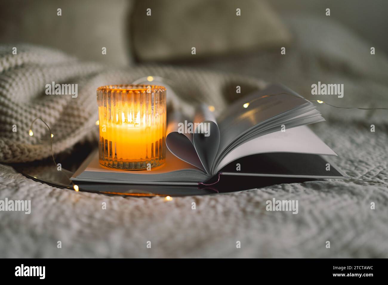 Scented candle with book with folded sheets in heart shape in bed Stock ...