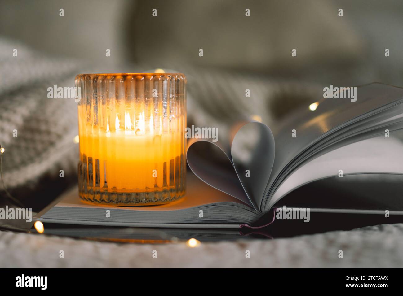 Scented candle with book with folded sheets in heart shape in bed Stock ...
