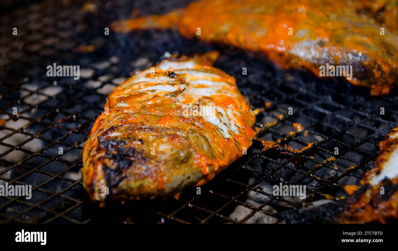 Hot mackerel fish on a grilling pan, with herb spices on coal fire in ...