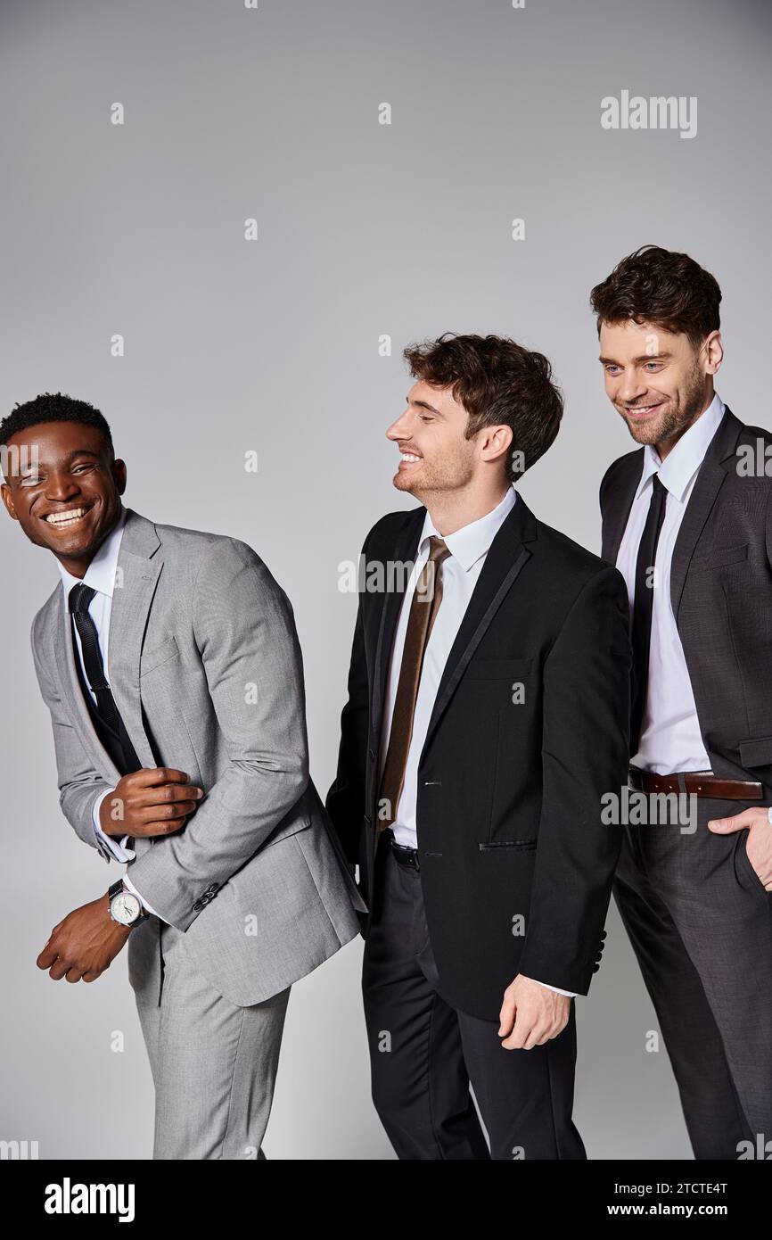 good looking cheerful multicultural male models in smart suits smiling ...