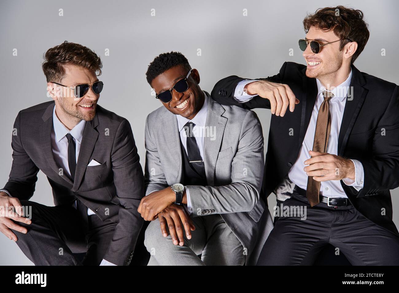 jolly attractive multicultural men in business smart suits sitting on ...