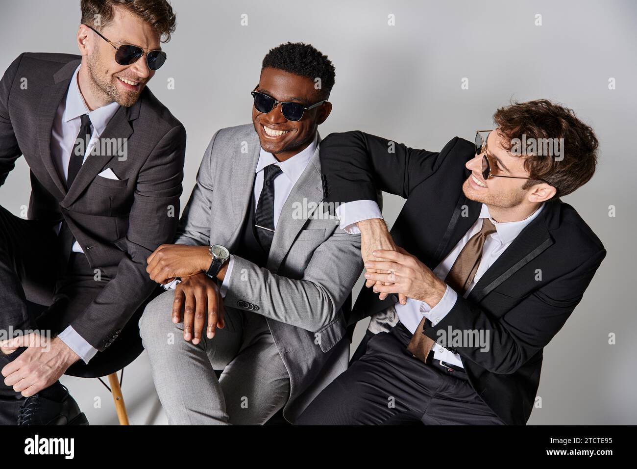happy good looking multicultural men in business smart suits sitting on ...