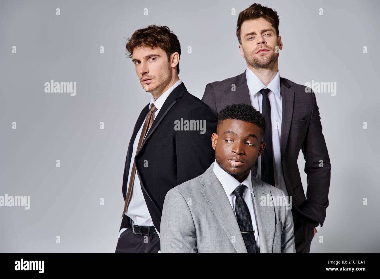 handsome young multicultural male models in business casual attires posing on gray backdrop ...