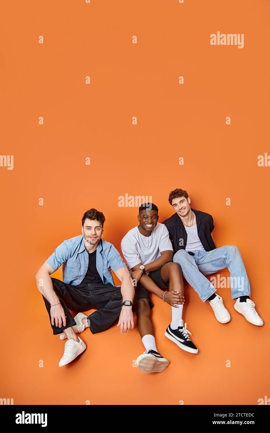 happy multiracial friends in casual street outfits sitting on floor and ...