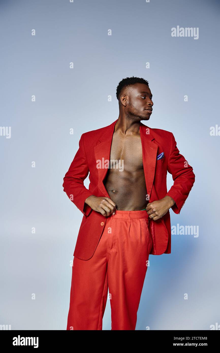handsome stylish african american man in red suit posing on gray ...